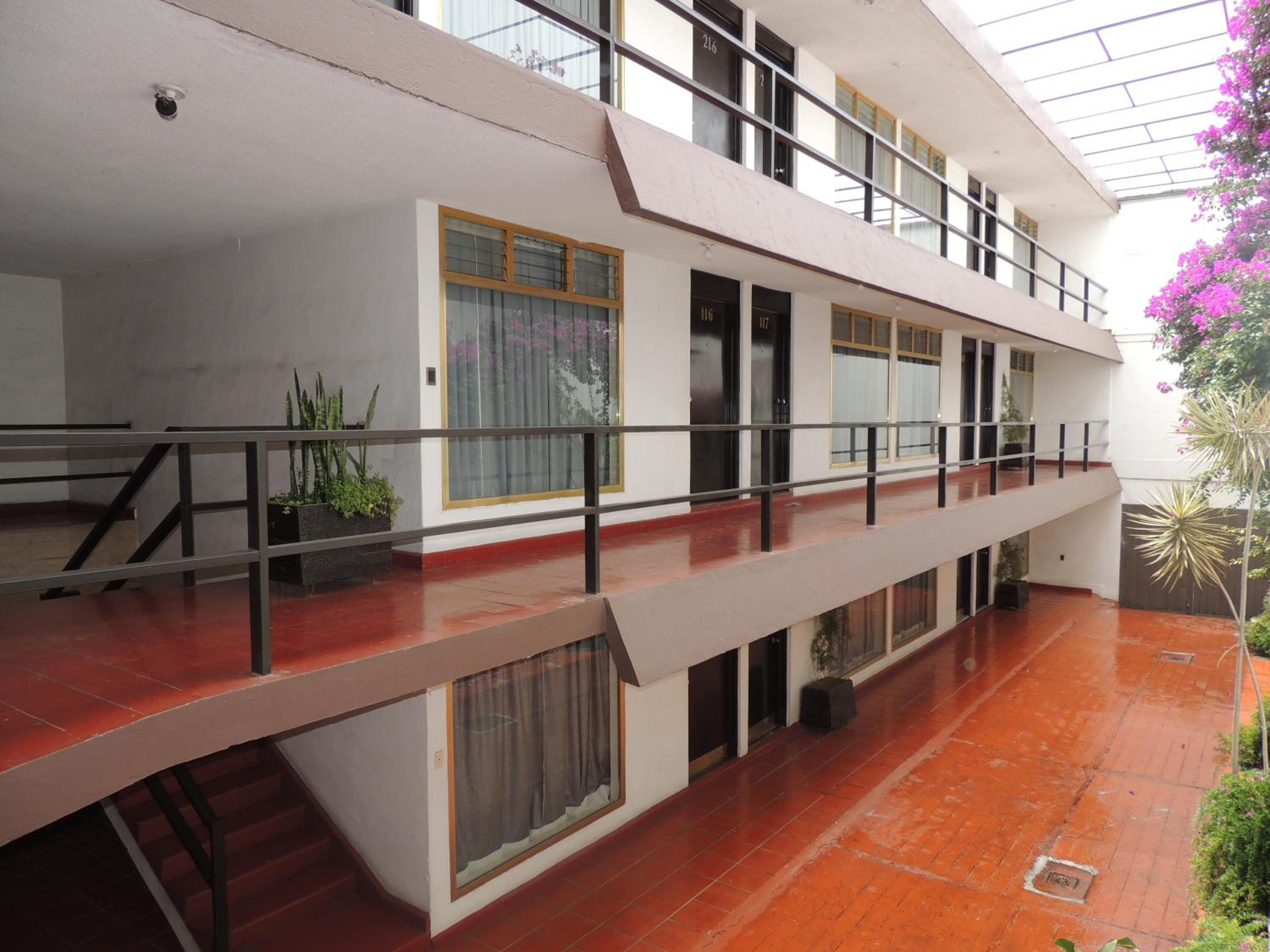 Um edifício com vários andares, varandas, janelas amplas e plantas dentro de casa.