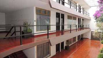Um edifício com vários andares, varandas, janelas amplas e plantas dentro de casa.