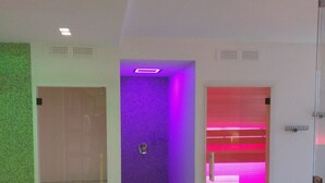 Um interior moderno com um corredor iluminado em roxo, uma parede texturizada em verde e um quarto iluminado em vermelho.