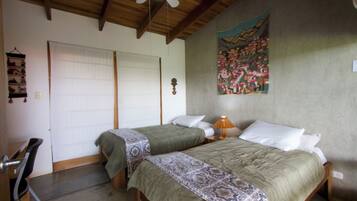 Quarto com duas camas, uma escrivaninha e um ventilador de teto.