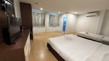 Quarto de hotel com uma cama grande, televisão, escrivaninha e guarda-roupa.