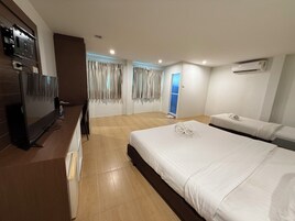 Quarto de hotel com uma cama grande, televisão, escrivaninha e guarda-roupa.