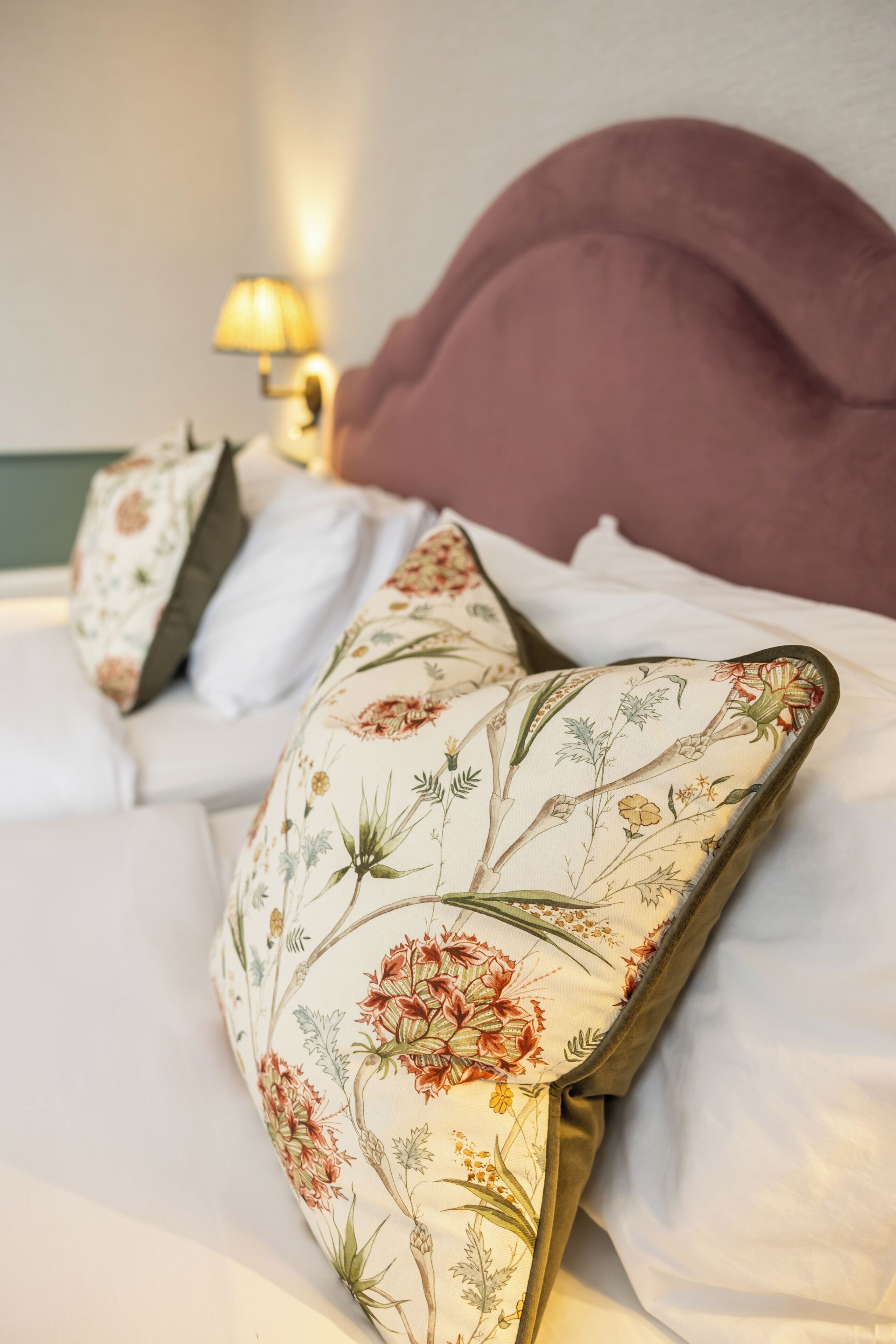 Cama com almofadas estampadas e cabeceira.