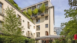Um edifício com um jardim no telhado, um pequeno espelho d'água e área de estar ao ar livre.