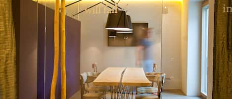 Uma sala de reuniões moderna com uma mesa comprida, cadeiras e uma luminária pendente.