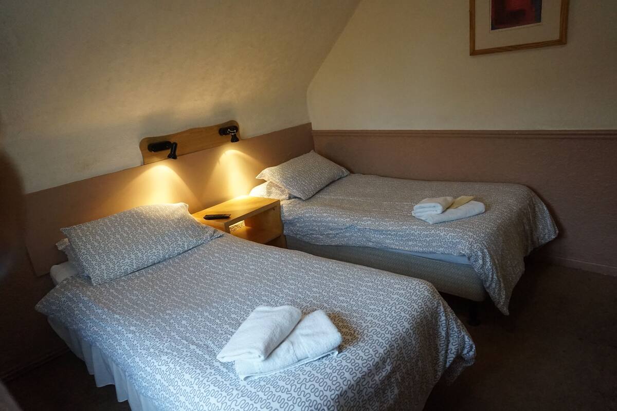 Quarto com duas camas, cada uma com cabeceira e mesa de cabeceira.