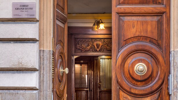 Uma porta de madeira com uma placa acima que diz "CORSO GRAND SUITE 1 Piano - Int. 2".
