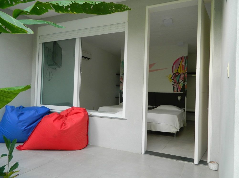 Quarto com cama, janela e um puff.