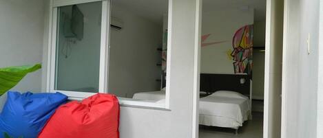 Quarto com cama, janela e um puff.