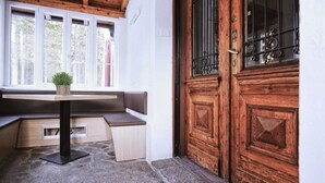 Uma porta de madeira com portão de metal, um banco e uma mesa com uma planta.