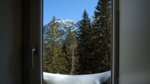 Visão através de uma porta para uma paisagem nevada, com uma montanha ao fundo.