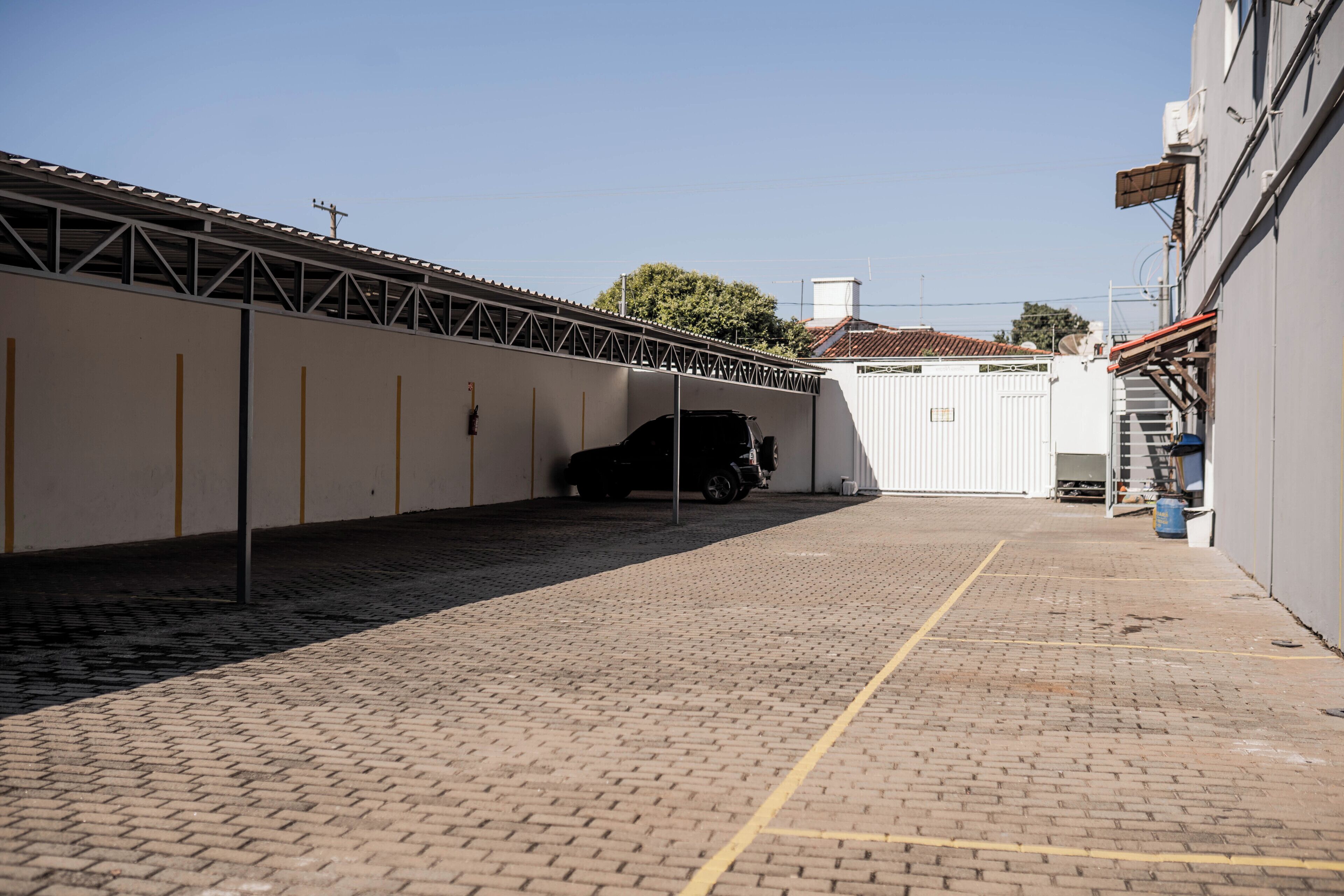Uma área de estacionamento com pavimento e um veículo estacionado.