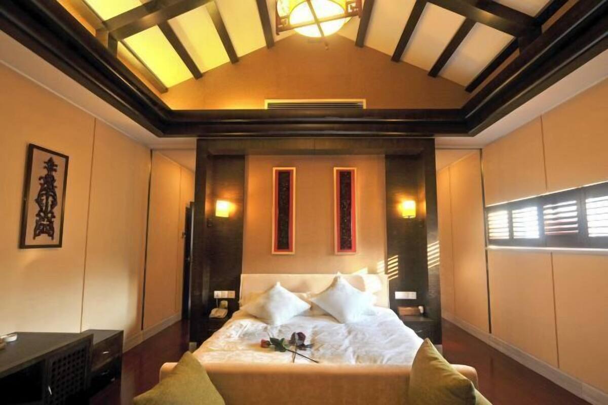 Quarto de hotel com uma cama grande, uma escrivaninha e teto com vigas de madeira.