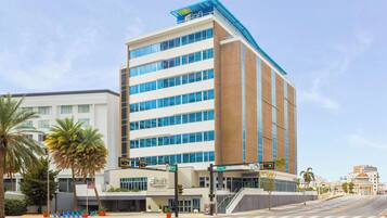 Um hotel moderno com uma placa chamativa da marca 'aloft', vários andares e um telhado plano.