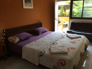 Quarto com cama, janela e porta para uma varanda.