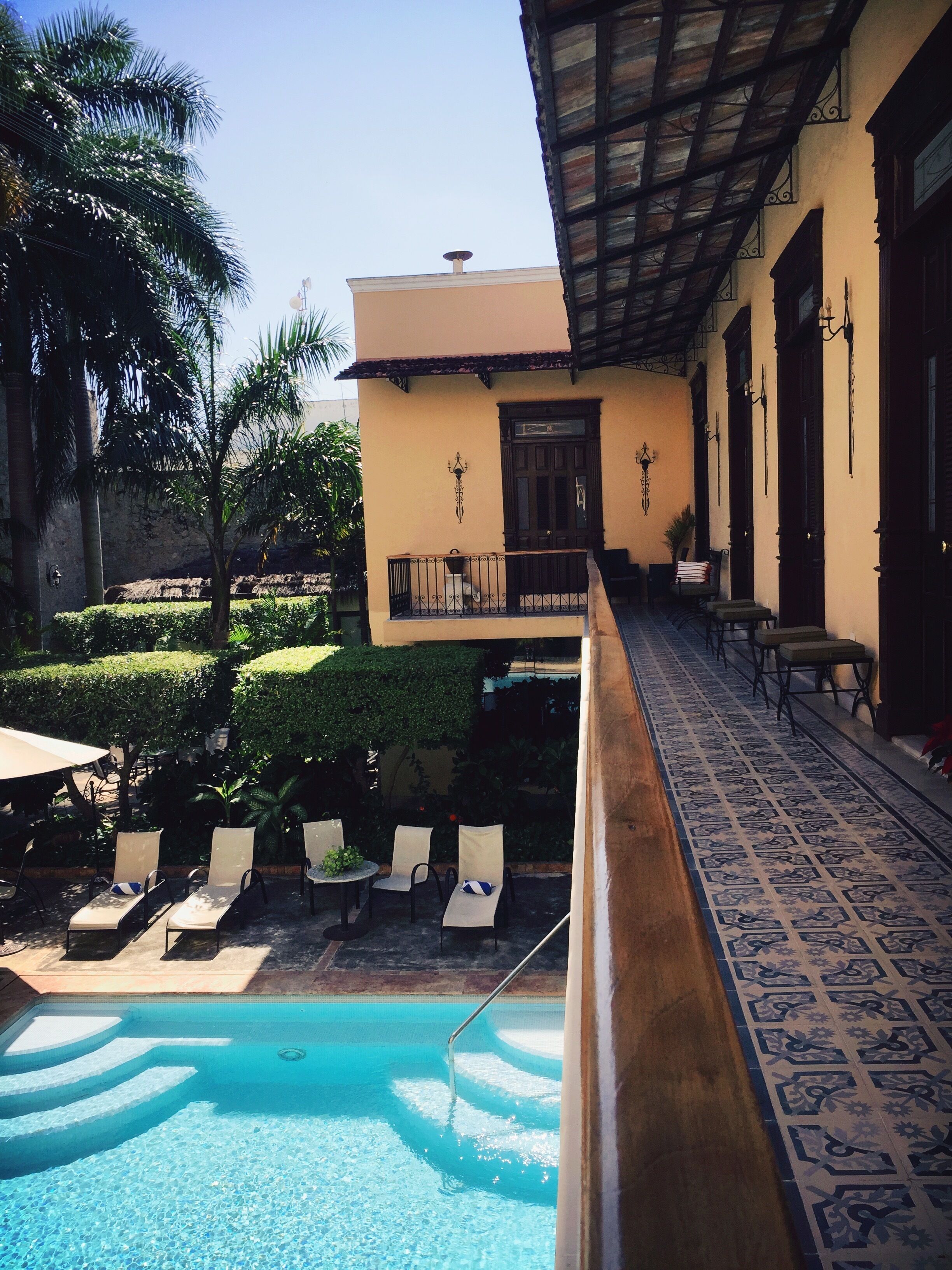 Uma área de piscina com espreguiçadeiras e um deck revestido de azulejos.