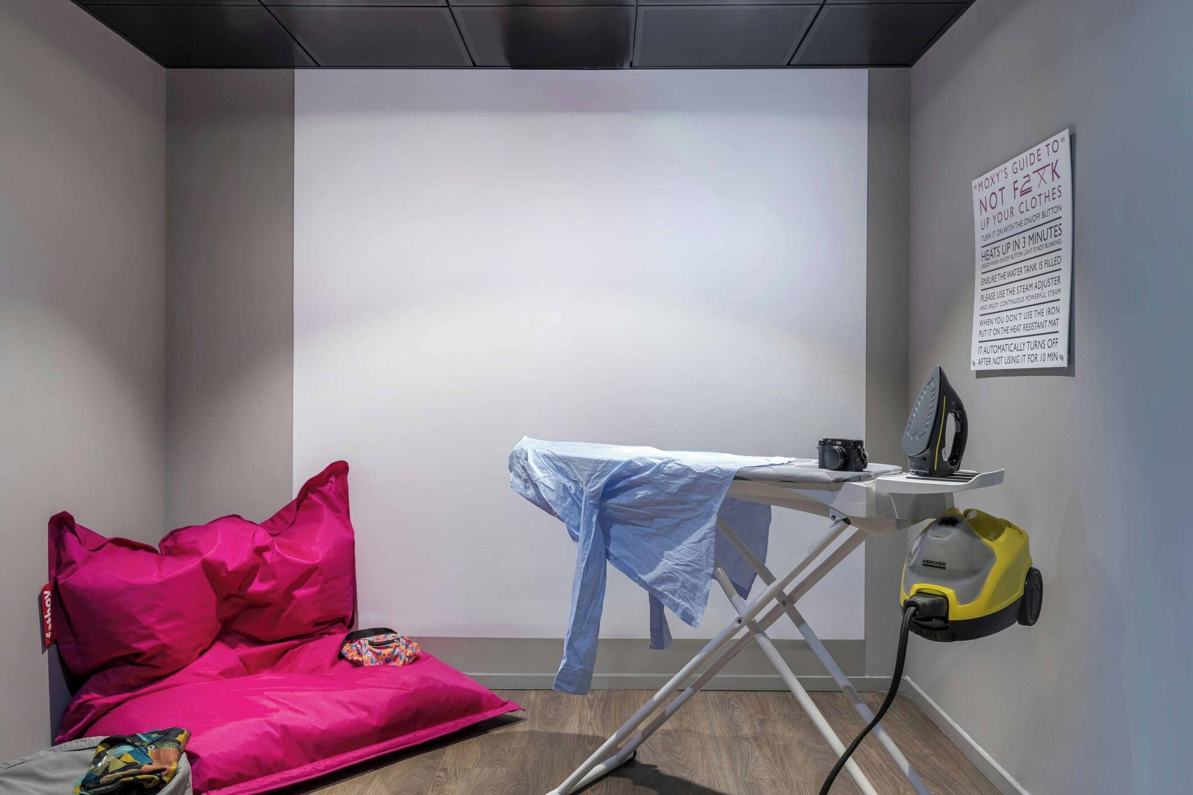 Quarto com cama, tábua de passar e aspirador de pó.