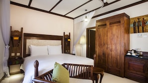 Quarto com cama grande, cabeceira de madeira, armário de madeira e uma pequena mesa com cadeira.