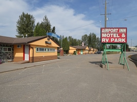 Um motel com uma placa indicando que é uma hospedaria para viajantes do aeroporto e parque para veículos recreativos.