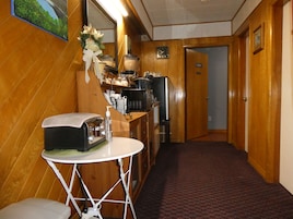 Um hall de hotel com piso de madeira, balcão de recepção, máquina de café e espelho.