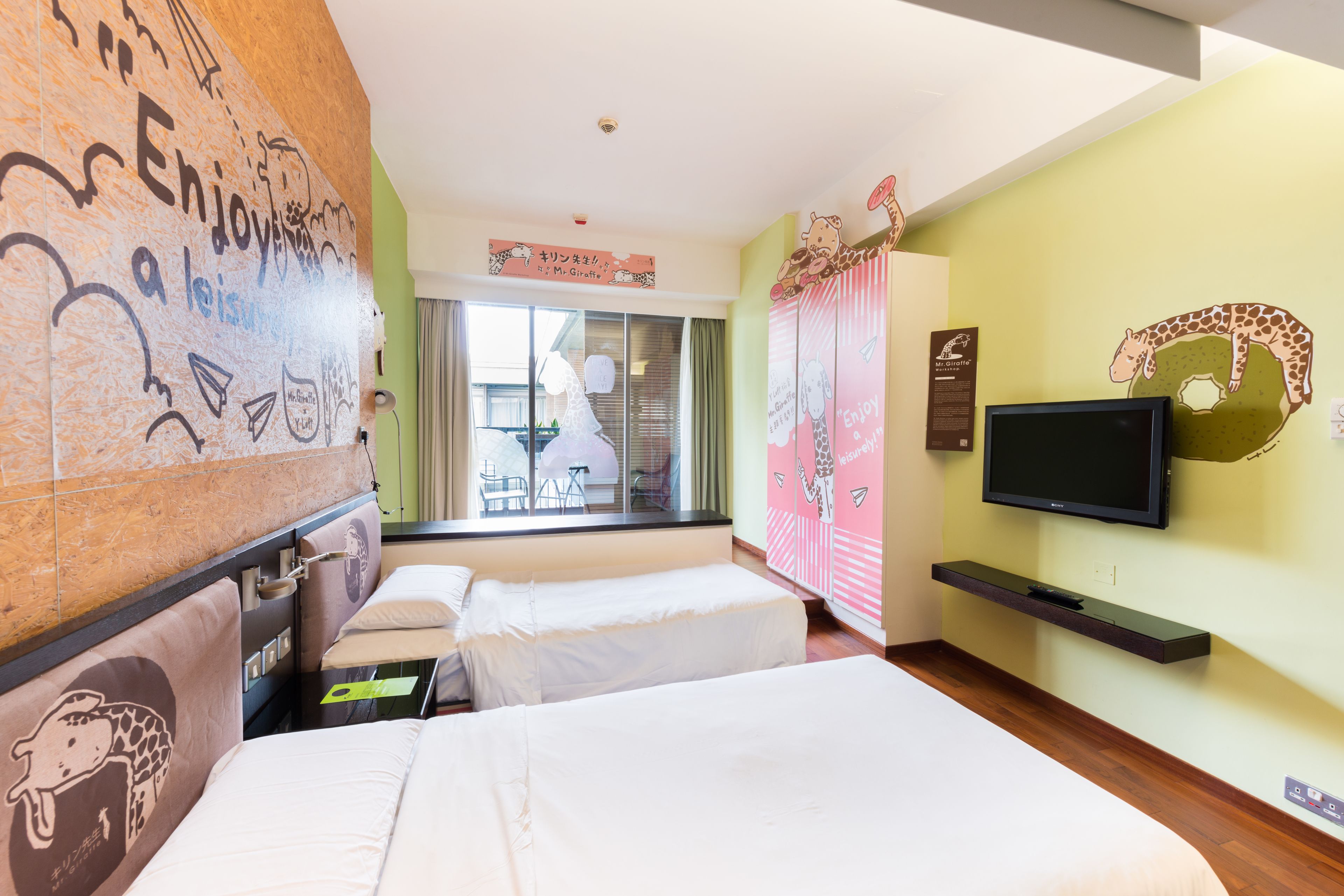 Quarto de hotel com duas camas, televisão e janela com vista para o exterior.