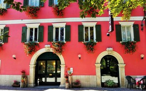 Um edifício com fachada vermelha, persianas verdes e caixas de flores.