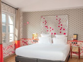 Quarto com cama, mesa de cabeceira, espelho e janela com cortinas.