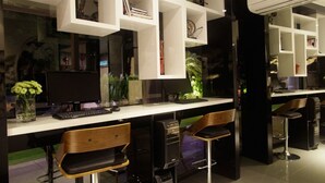Espaço de trabalho moderno com escrivaninha, duas cadeiras e estantes abertas com livros e objetos decorativos.