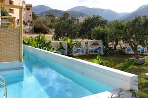 Piscina com vista para montanhas, rodeada por espreguiçadeiras e vegetação.
