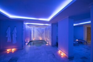 Um spa moderno com piso de mármore, banheira de hidromassagem e velas.