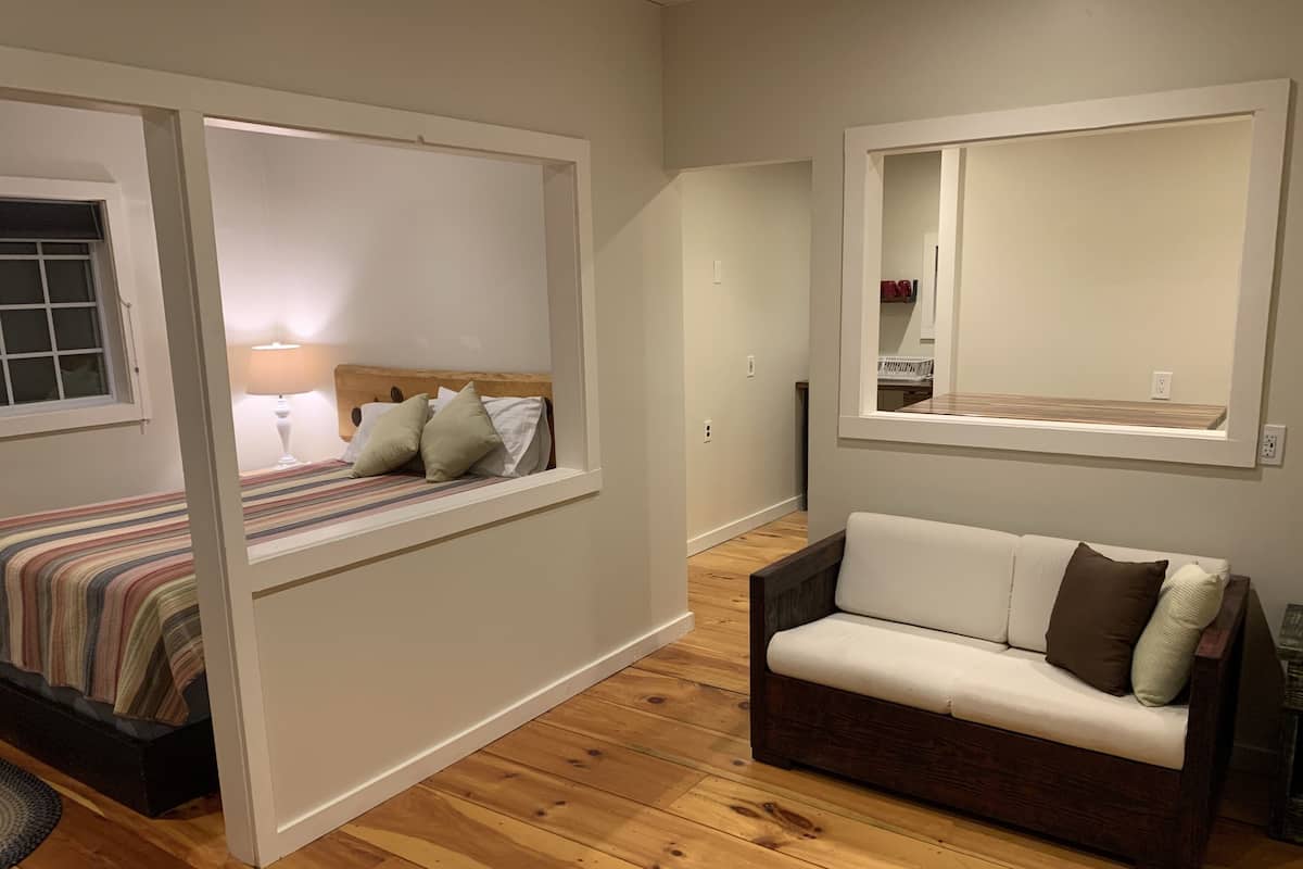Um quarto com uma cama, um sofá, uma janela e um espelho.
