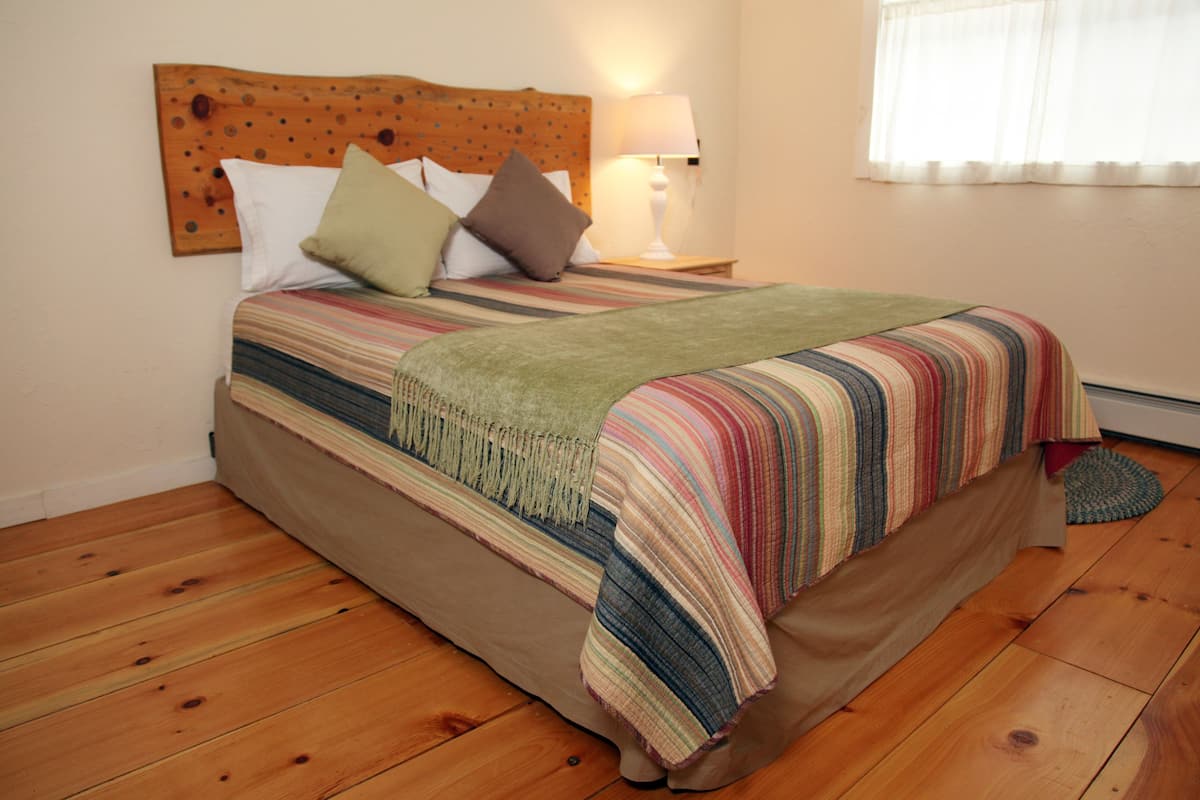 Uma cama bem arrumada com um edredom listrado, uma cabeceira de madeira e um abajur.