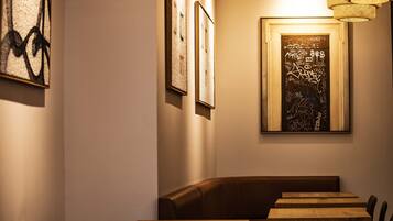 Interior de restaurante com área de assentos em cabines, mesas de madeira e obras de arte emolduradas nas paredes.