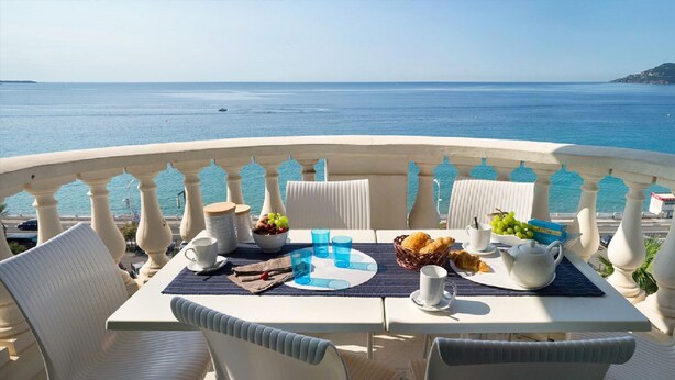 Varanda com mesa posta para o pequeno-almoço com vista para o mar.