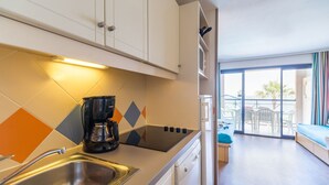 Cozinha moderna com cafeteira, lava-louças e área de jantar com banco e mesa.