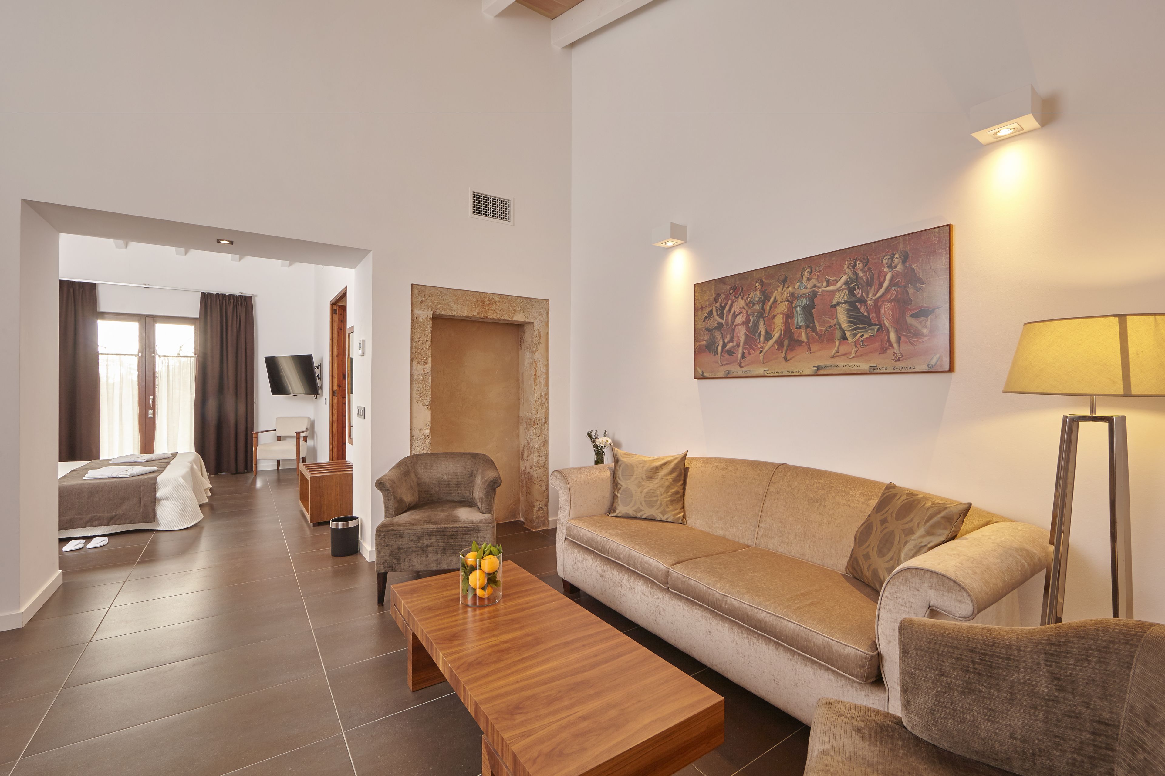 Uma sala de estar ampla com sofá, poltronas, mesa de centro de madeira e um quadro na parede.