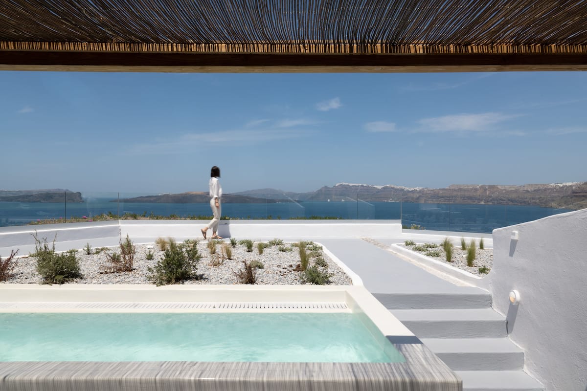 Uma área de piscina moderna ao ar livre, com vista clara para o mar e montanhas ao longe.