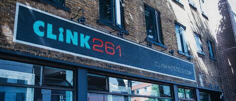 Um edifício com uma placa que diz "CLINK 261" e "CLINKHOSTELS.COM".