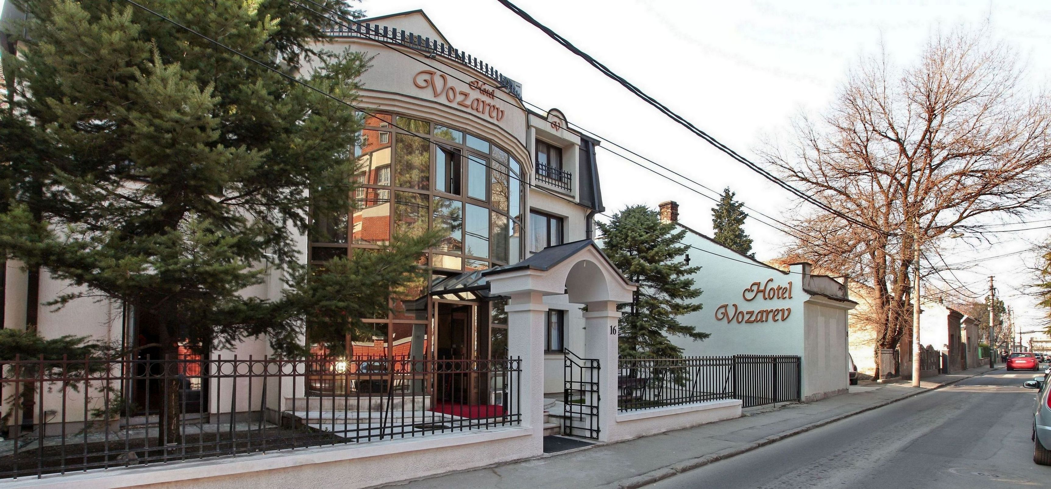Um edifício de hotel com fachada curva, grandes janelas e uma placa com a inscrição 'Hotel Vozarev'.