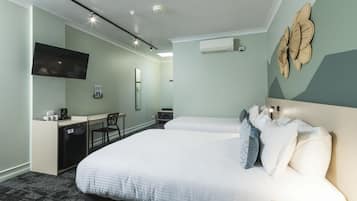 Quarto de hotel com uma cama grande, uma escrivaninha, uma cadeira, televisão de tela plana e ar condicionado.