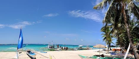Na praia, praia de areia branca, espreguiçadeiras, guarda-sóis de praia