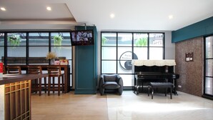 Um hall amplo com um piano, área de estar e uma tela de televisão.