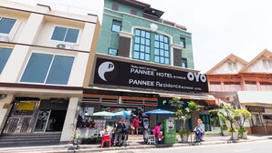Um hotel com uma grande placa indicando Pannée Hotel e OYO. Há áreas de estar ao ar livre e uma loja 7-Eleven.