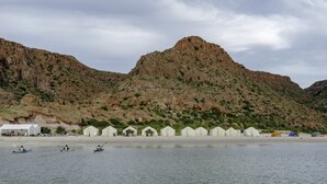 Uma praia com cabanas brancas e caiaques na margem.