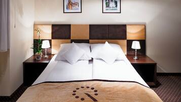 Quarto de hotel com uma cama grande, duas mesas de cabeceira, um cobertor decorativo em formato de relógio e duas fotografias emolduradas na parede.