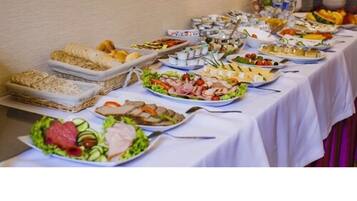 Mesa de buffet com diversos alimentos e recipientes.