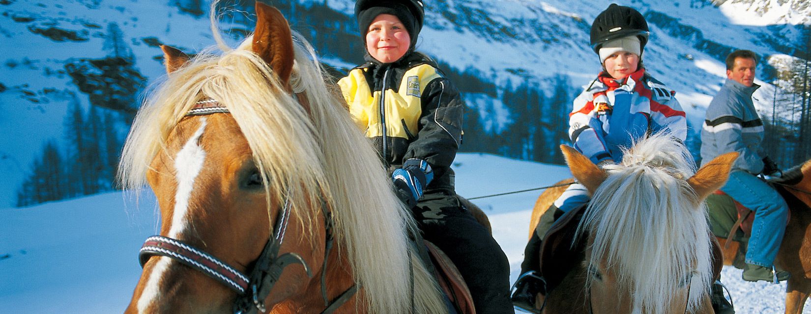 Um grupo de pessoas a cavalo em uma paisagem nevada.