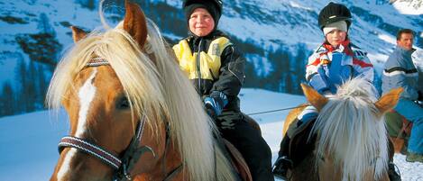 Um grupo de pessoas a cavalo em uma paisagem nevada.