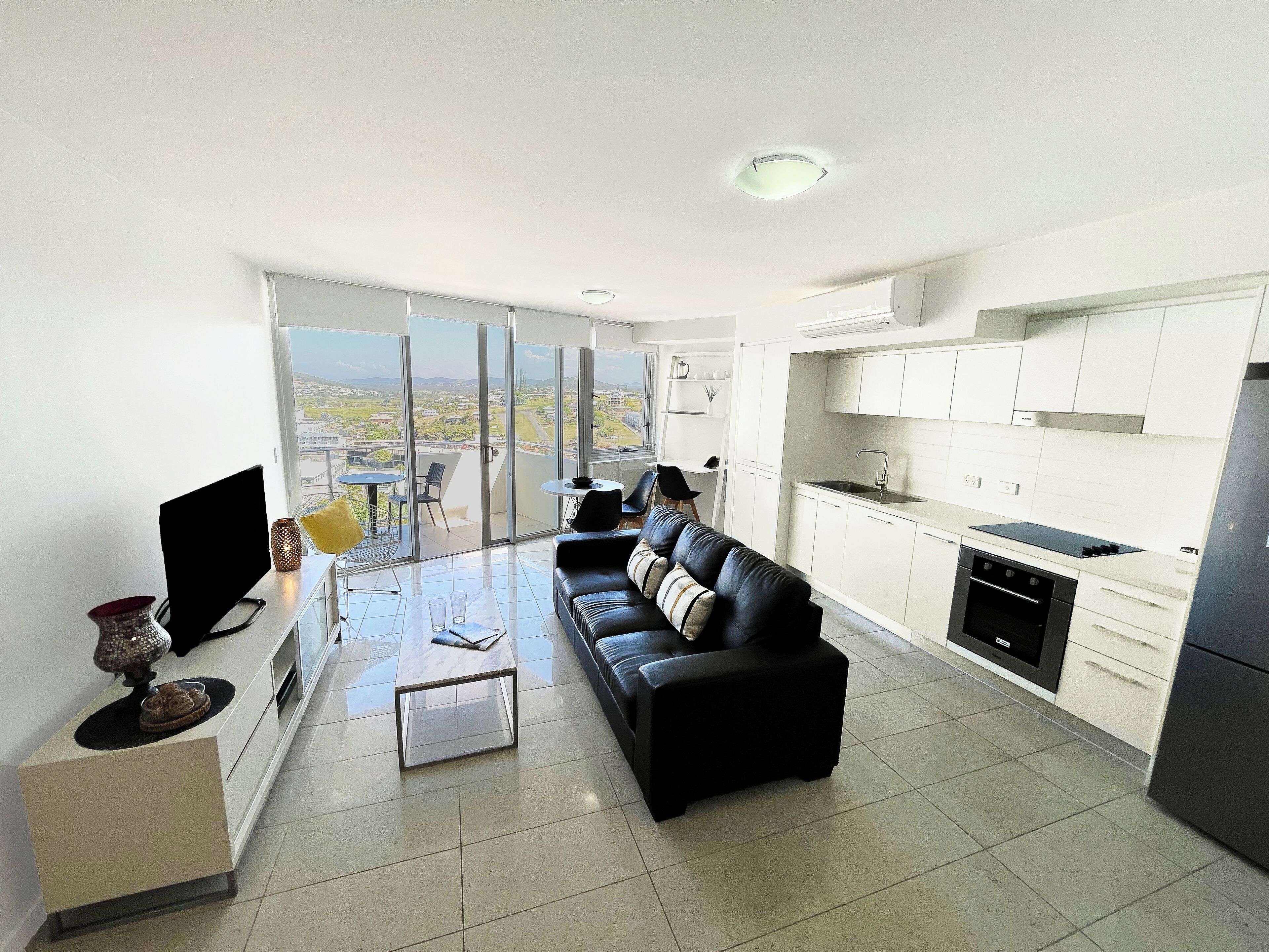 Um apartamento moderno com sala de estar, varanda com vista para a cidade, cozinha e área de refeições.