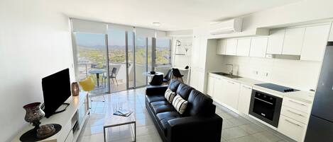 Um apartamento moderno com sala de estar, varanda com vista para a cidade, cozinha e área de refeições.